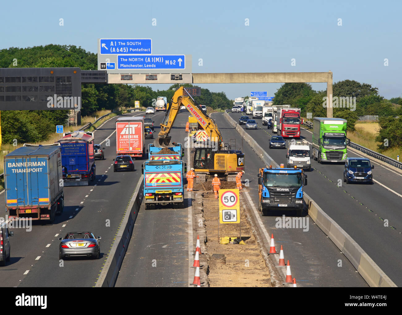 digger working in central reservation loading lorry's with rubble ...