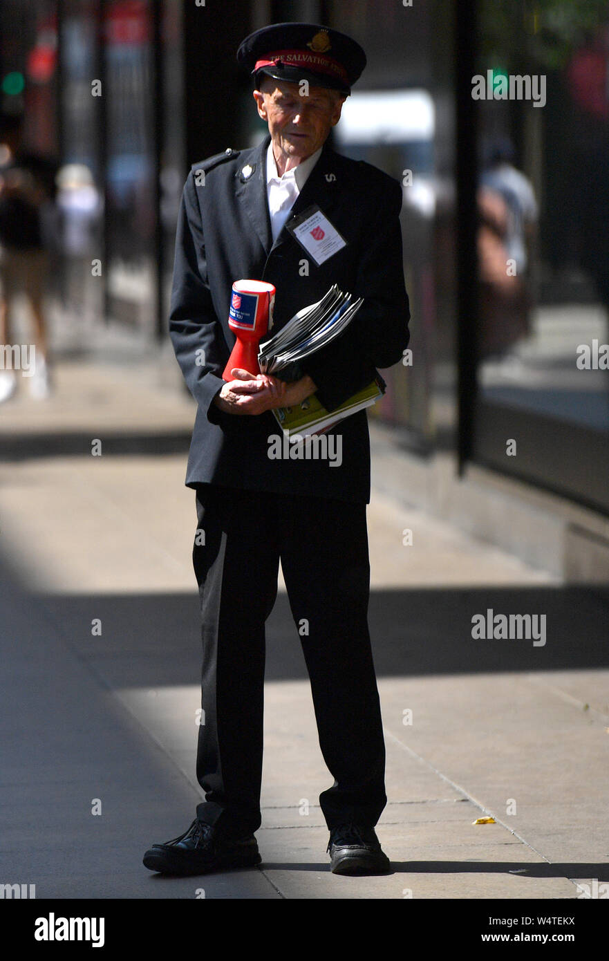A Salvation Army volunteer in full uniform collects donations in ...