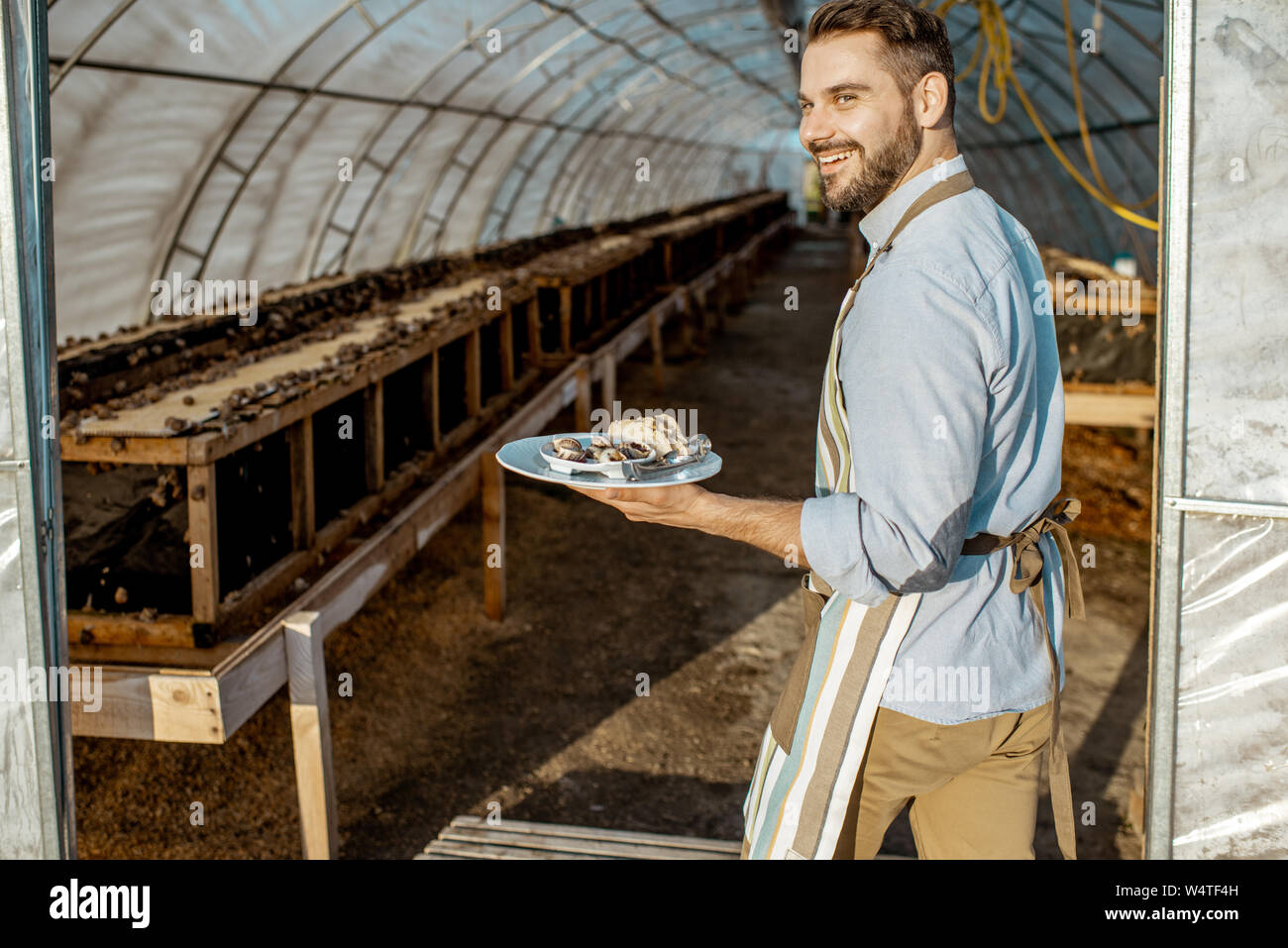 Portrait of a handsome chef cook standing with cooked snails in the ...