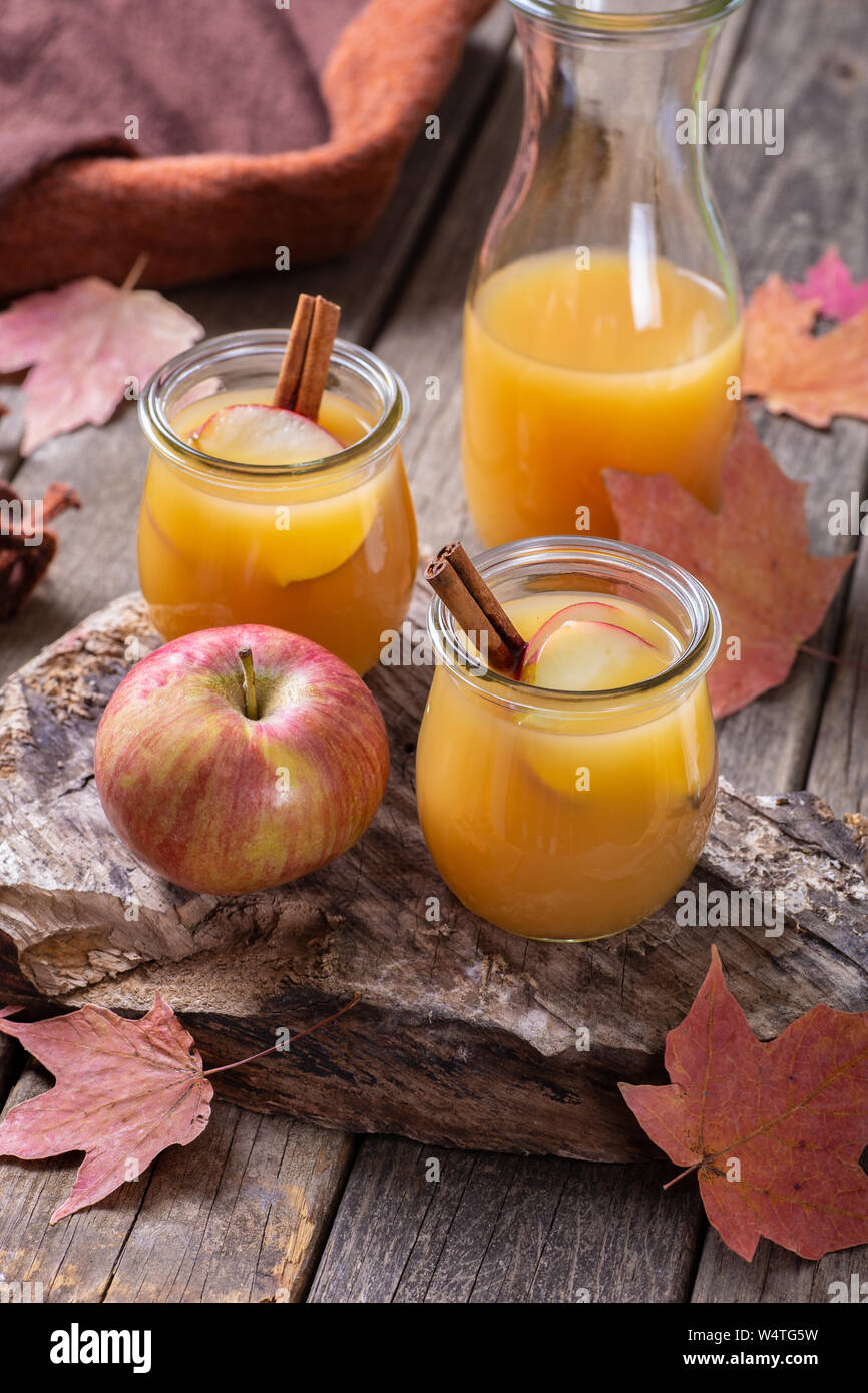 Two glass jars of apple cider with cinnamon sticks and apple slices on ...