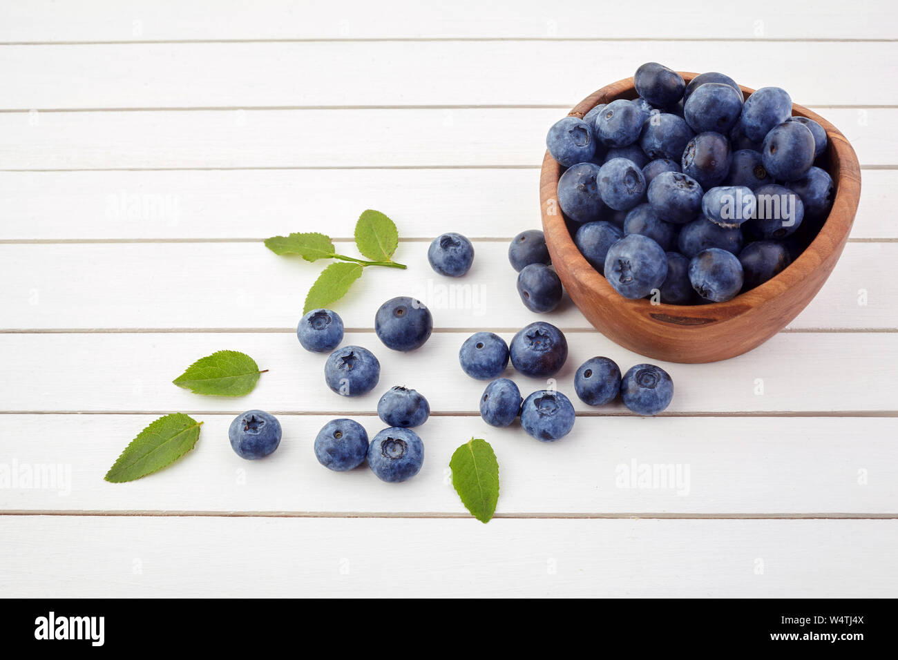 Fresh raw blueberries with leaves on white wooden background Stock ...