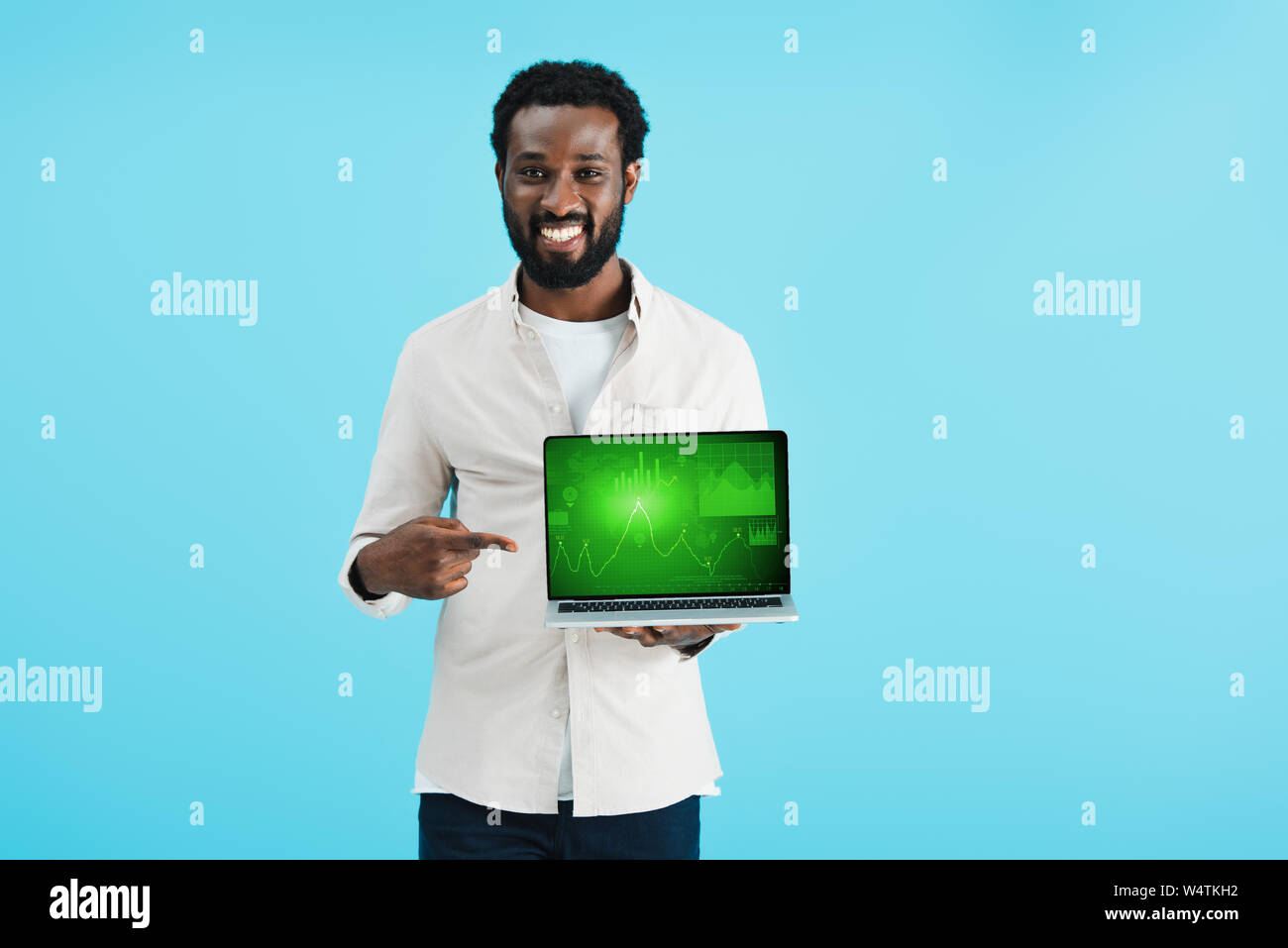 smiling african american man pointing at laptop with graph isolated on ...
