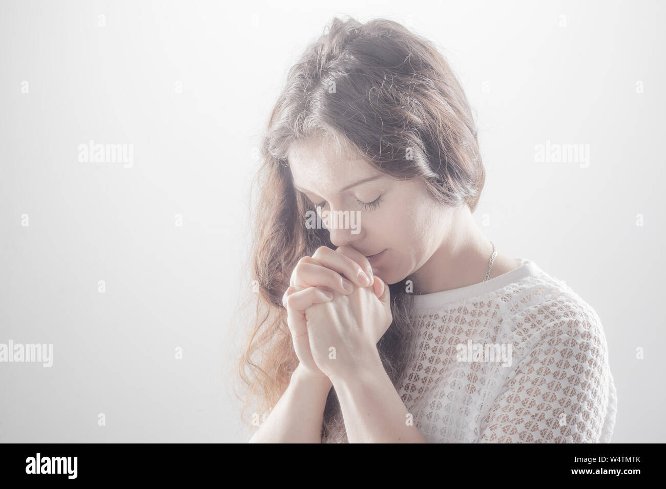 Praying woman on white background with shine Stock Photo - Alamy