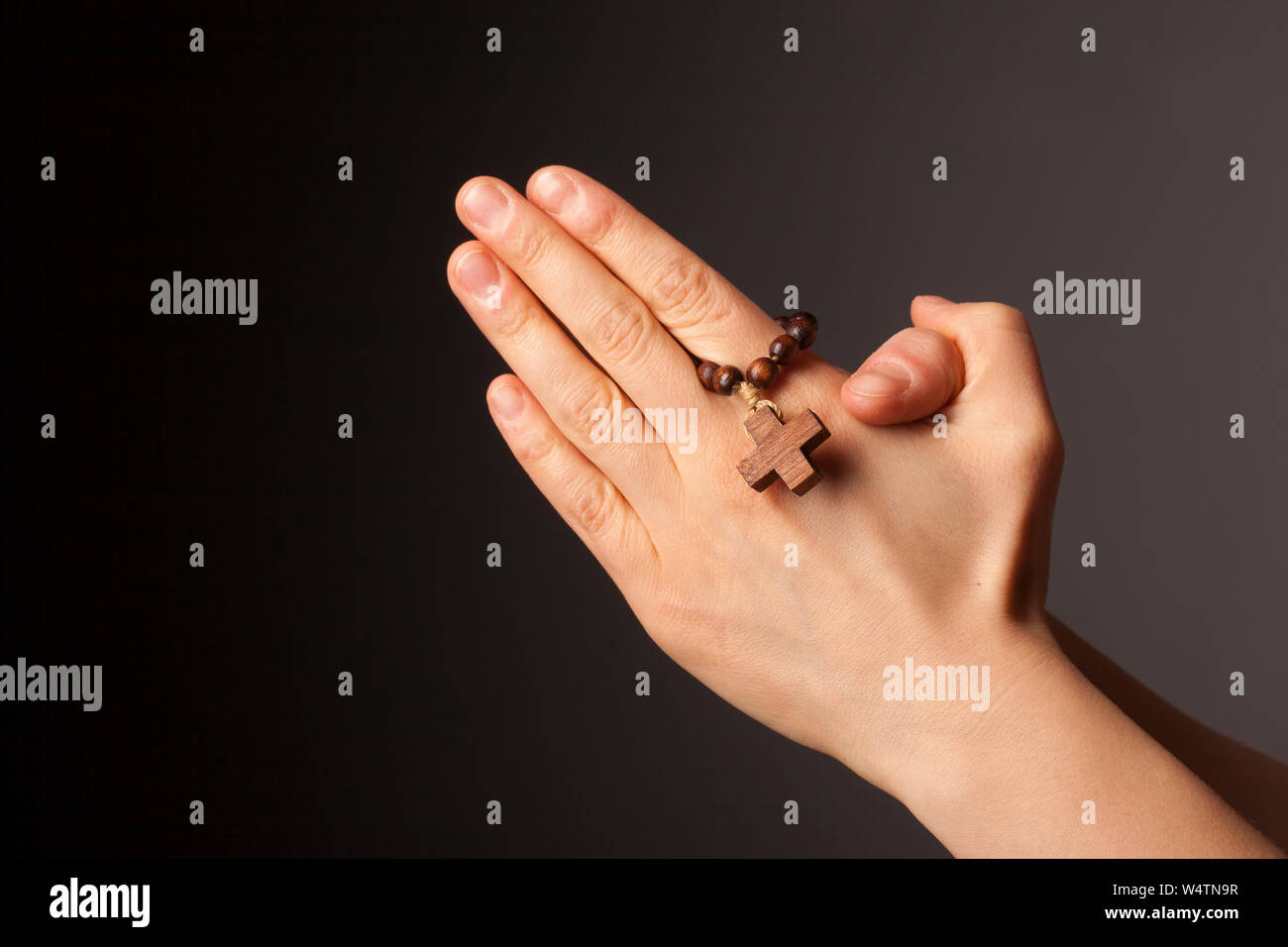 Hands with cross on dark background Stock Photo - Alamy