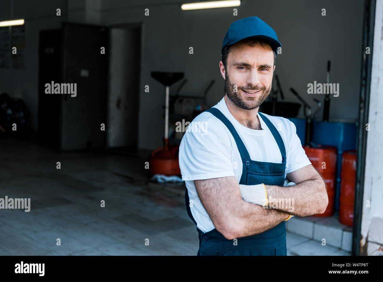 happy bearded car mechanic standing with crossed arms Stock Photo - Alamy