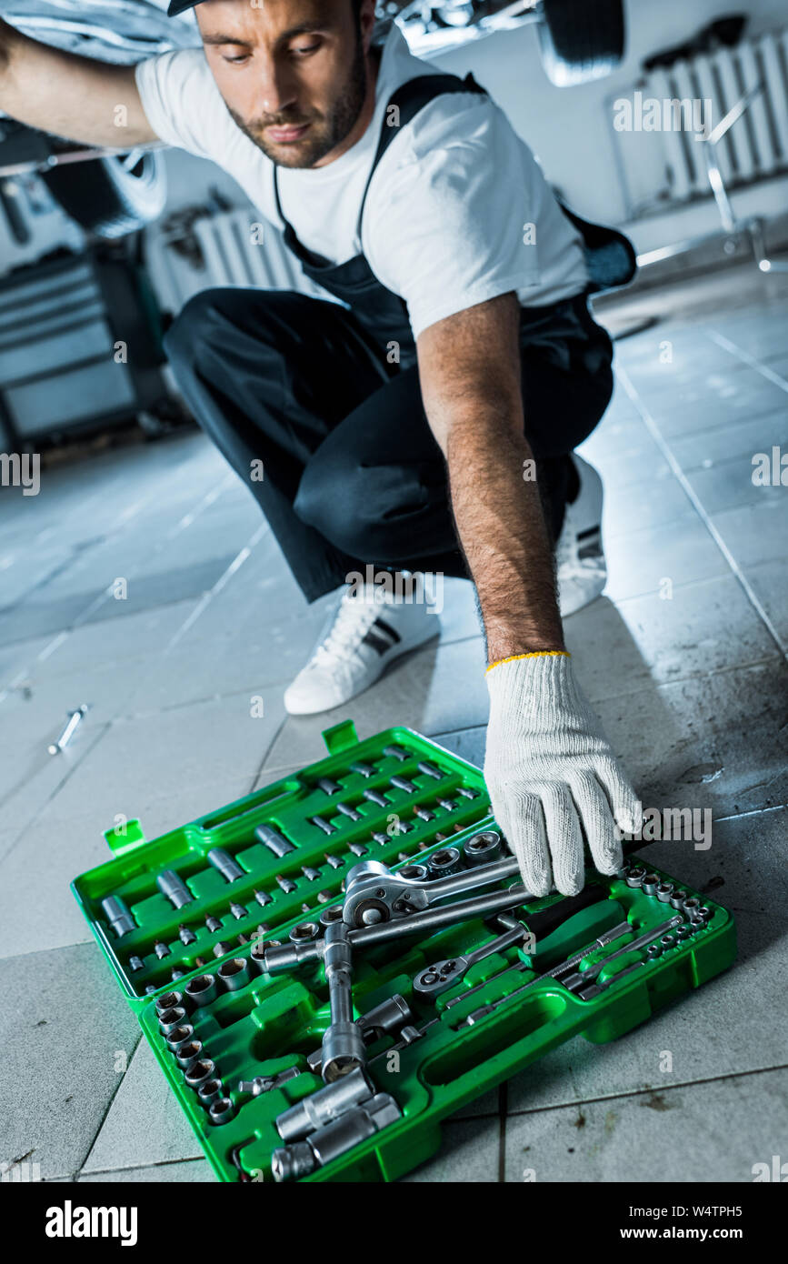 selective focus of auto mechanic taking metallic tool from toolbox ...