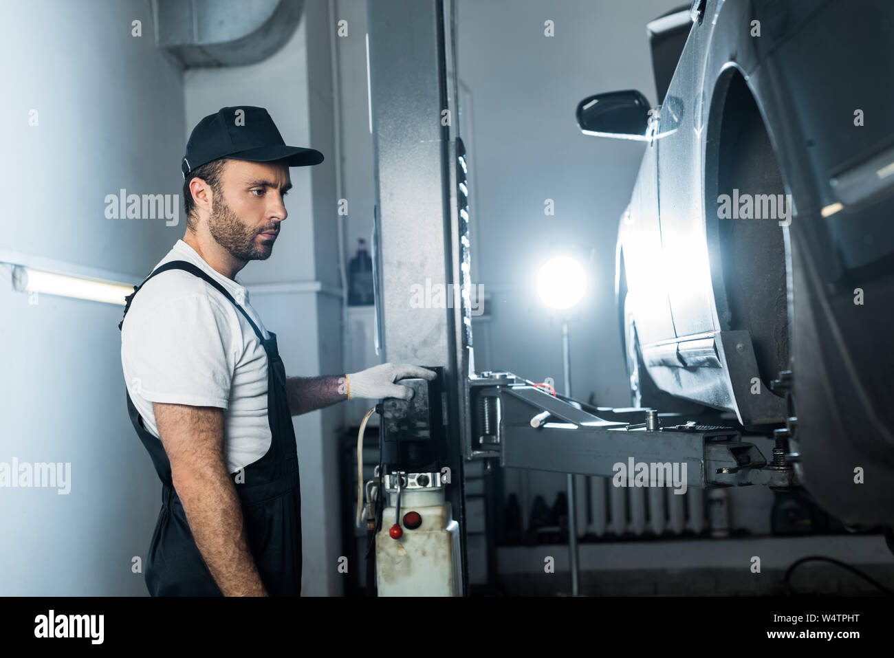 auto mechanic in cap standing near automobile in car service Stock ...