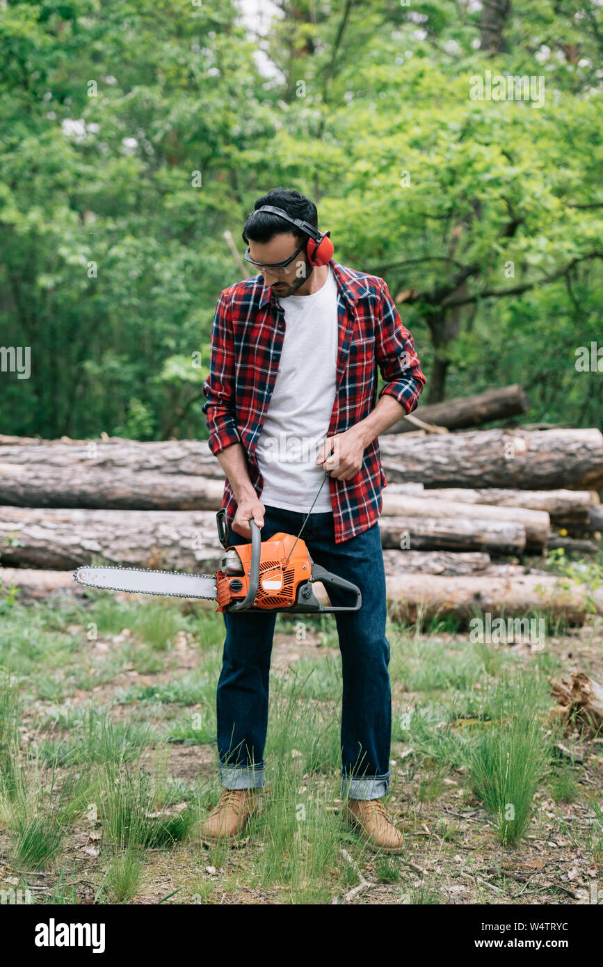 lumberjack in checkered shirt and noise-canceling headphones adjusting ...