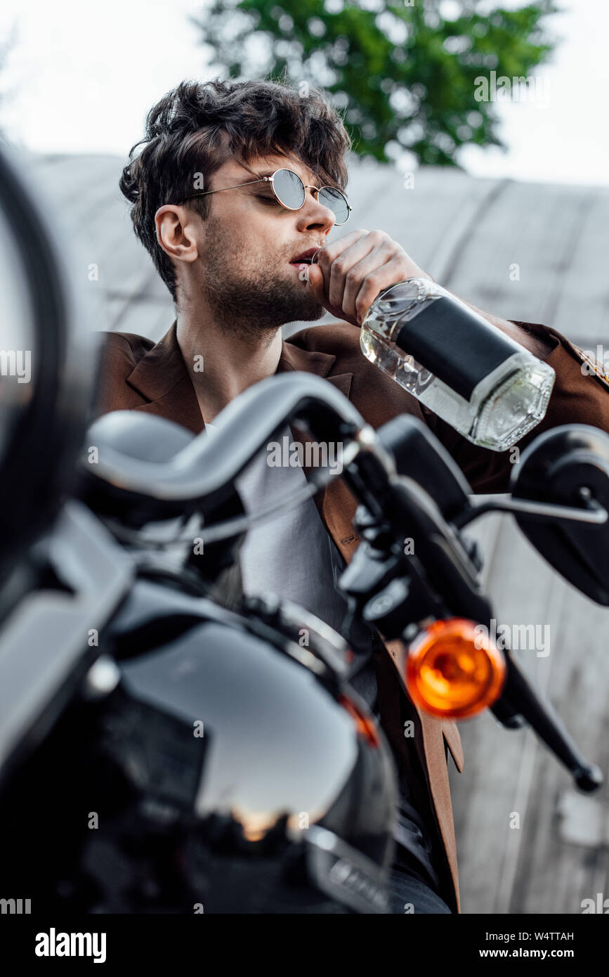 selective focus of handsome man drinking alcohol while sitting on ...