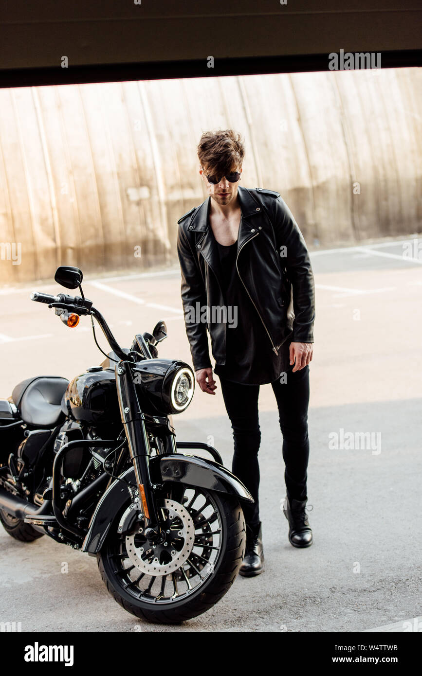 handsome young man walking to garage to black motorcycle Stock Photo ...