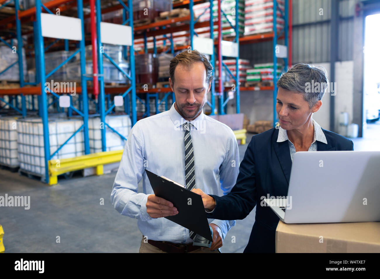 Staffs working together on laptop in warehouse Stock Photo - Alamy
