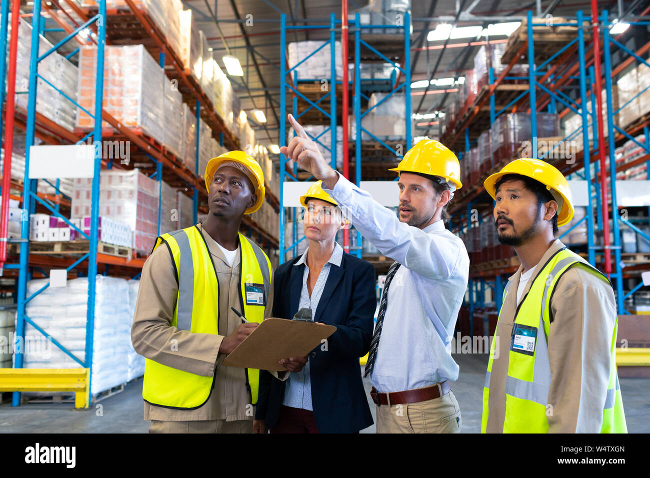 Male supervisor standing with coworkers and pointing at distance in ...
