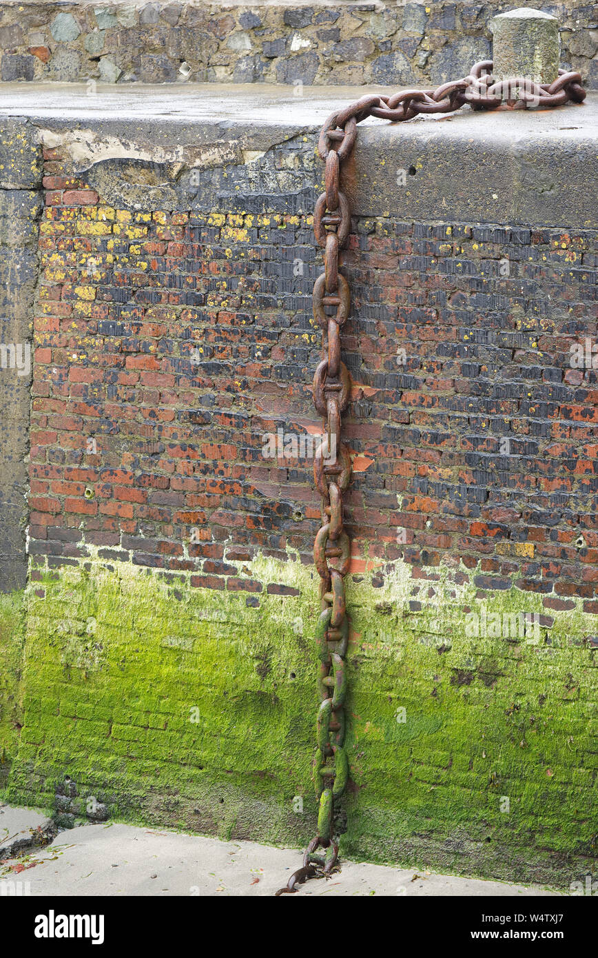 Large rusty old fishing boat chain hanging down the wet harbour (harbor ...
