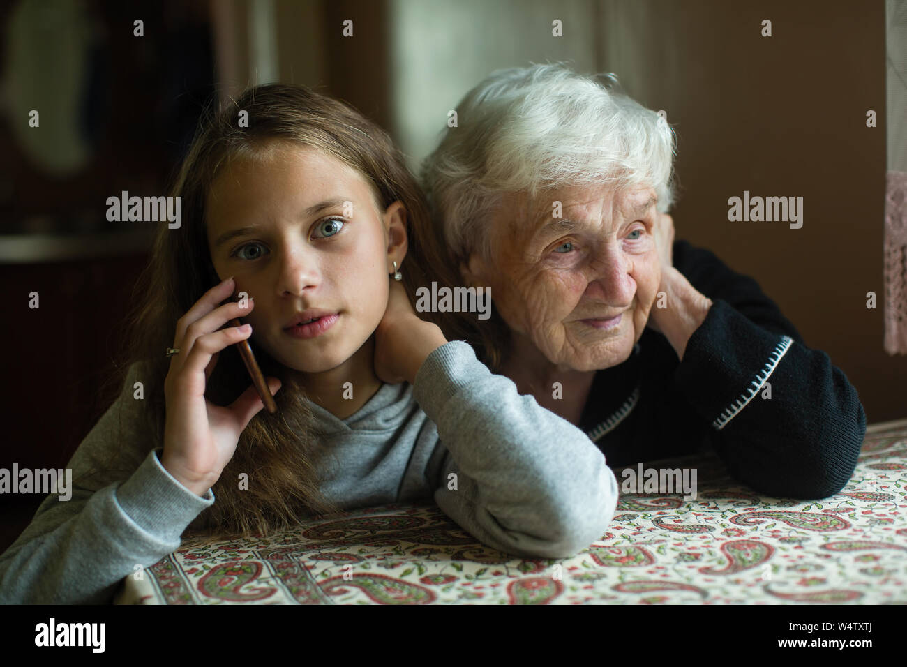 Little girl granddaughter talking on a mobile phone and grandmother her ...