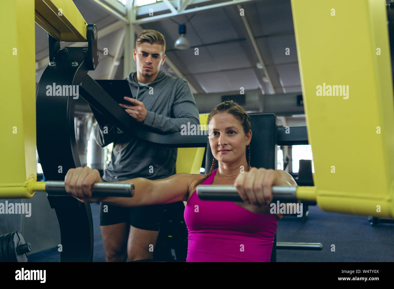 Trainer assisting female athlete with exercise in fitness studio Stock ...