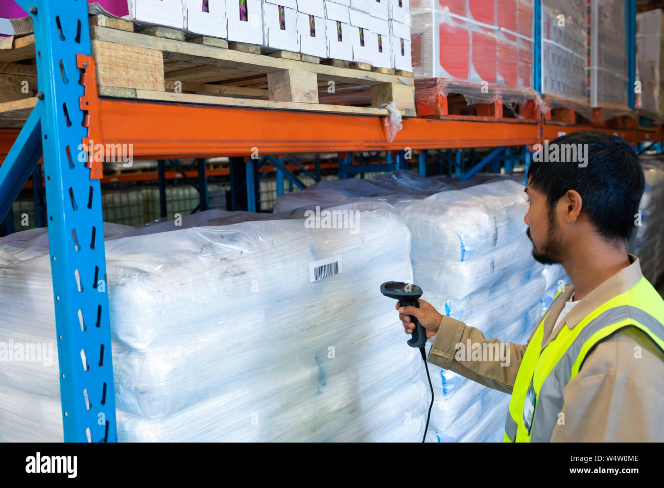Male worker scanning package with barcode scanner in modern warehouse ...