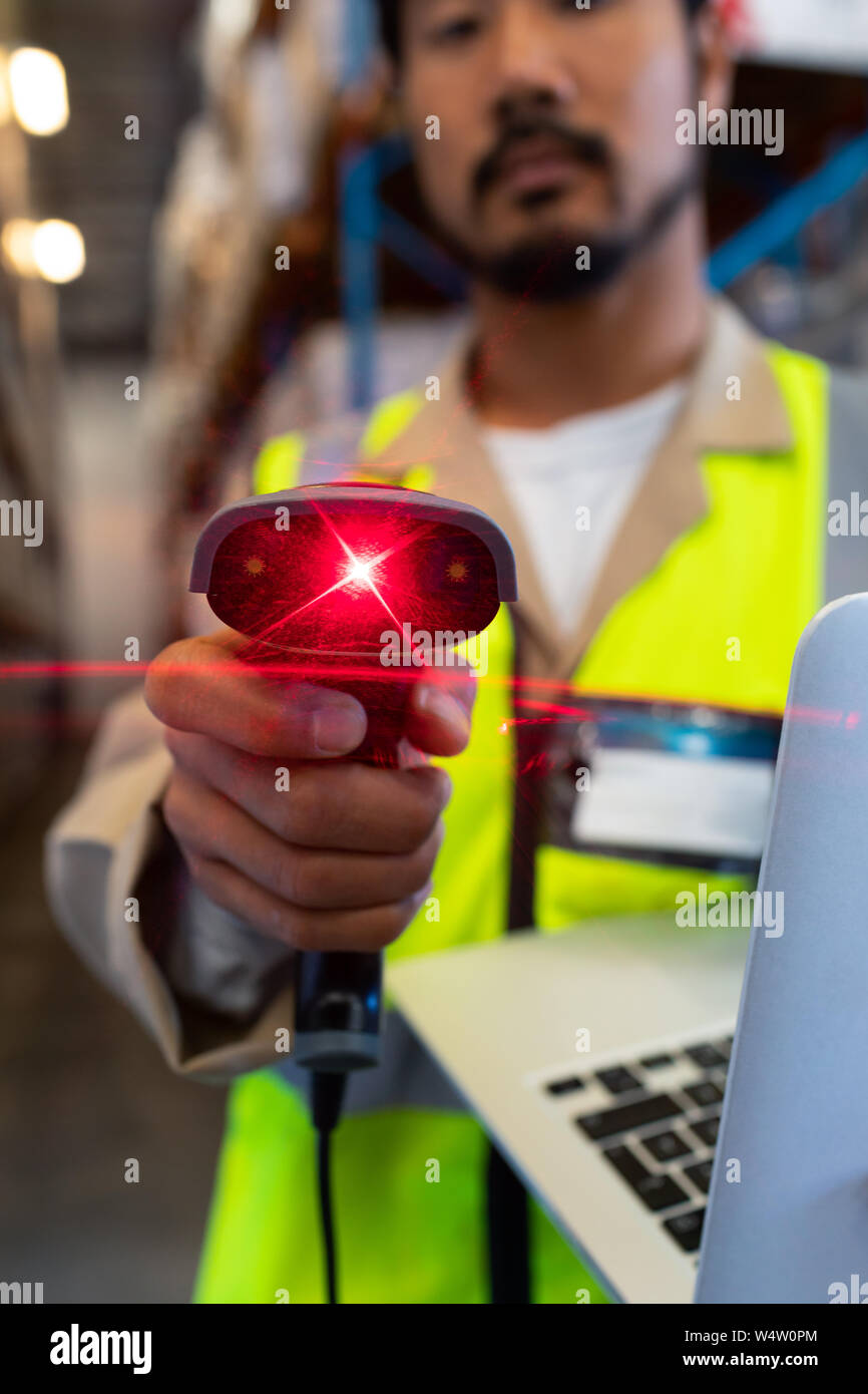 Male worker with laptop showing barcode scanner on camera in warehouse ...