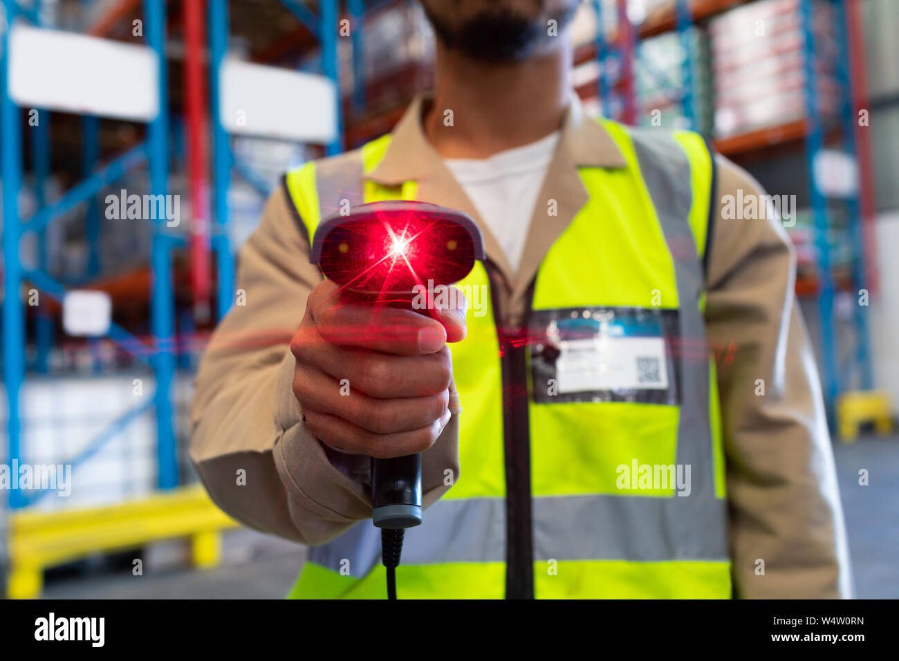 Male worker showing barcode scanner on camera in warehouse Stock Photo ...