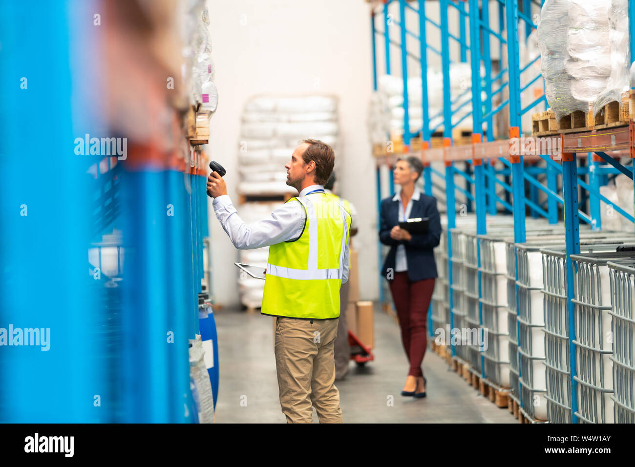 Male worker scanning package with barcode scanner in modern warehouse ...
