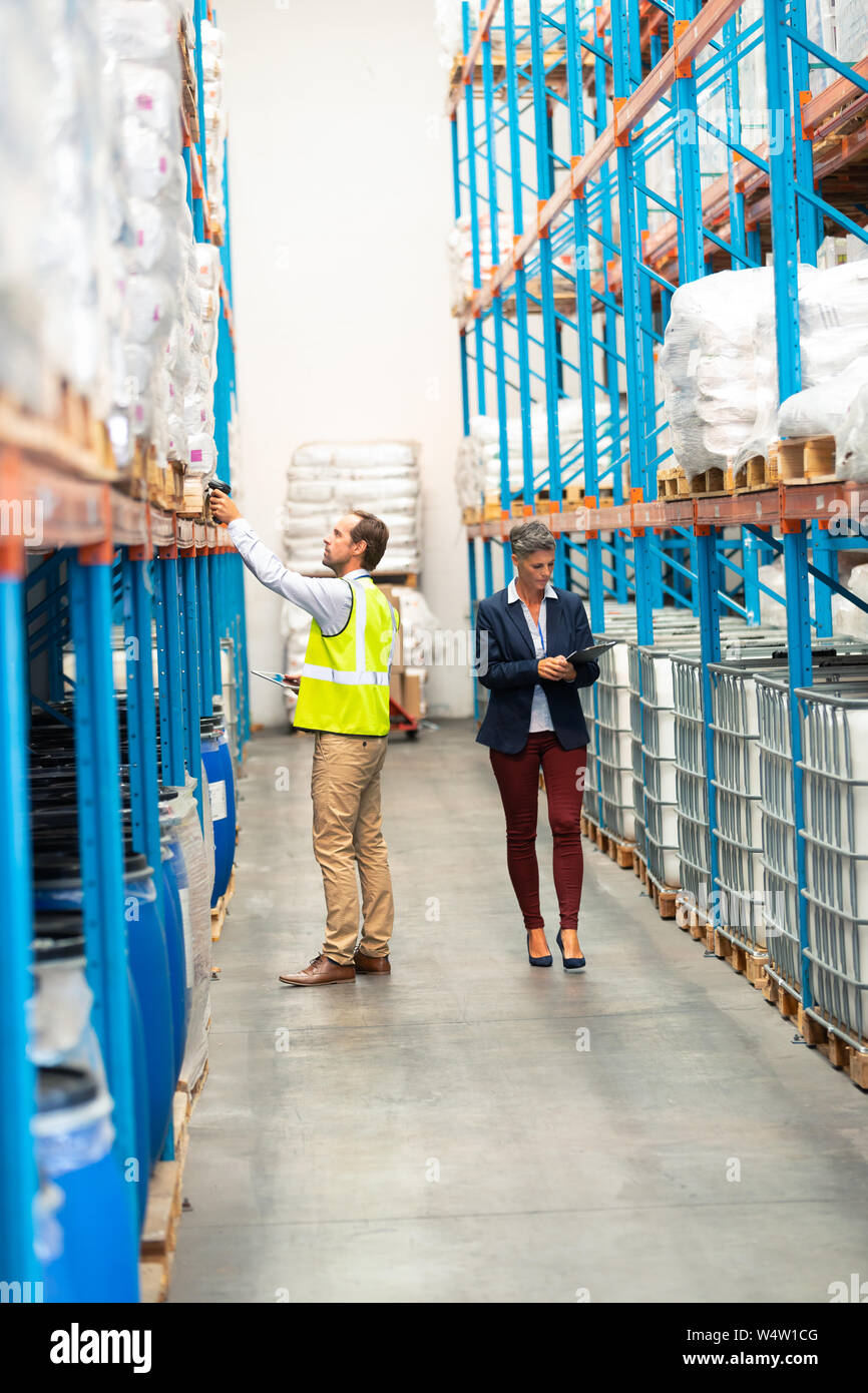 Male worker scanning package with barcode scanner in modern warehouse ...