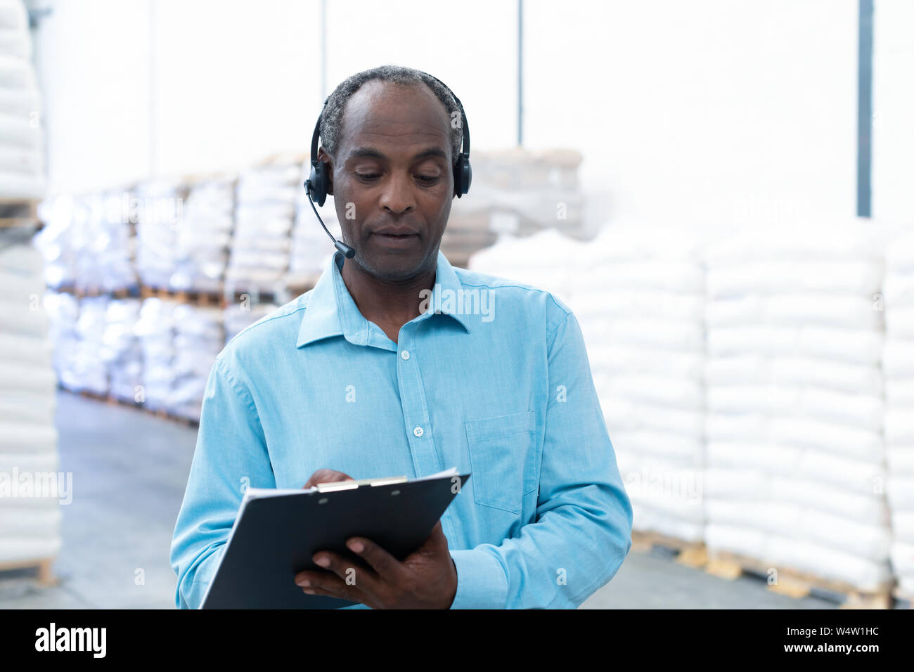 Male supervisor writing on clipboard in warehouse Stock Photo - Alamy