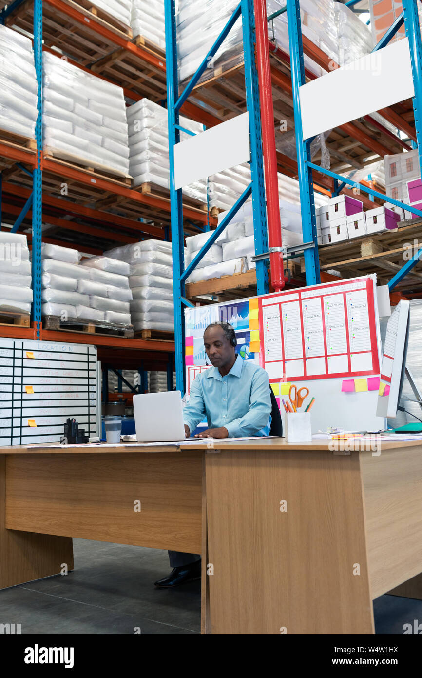 Male supervisor working on laptop at desk Stock Photo - Alamy