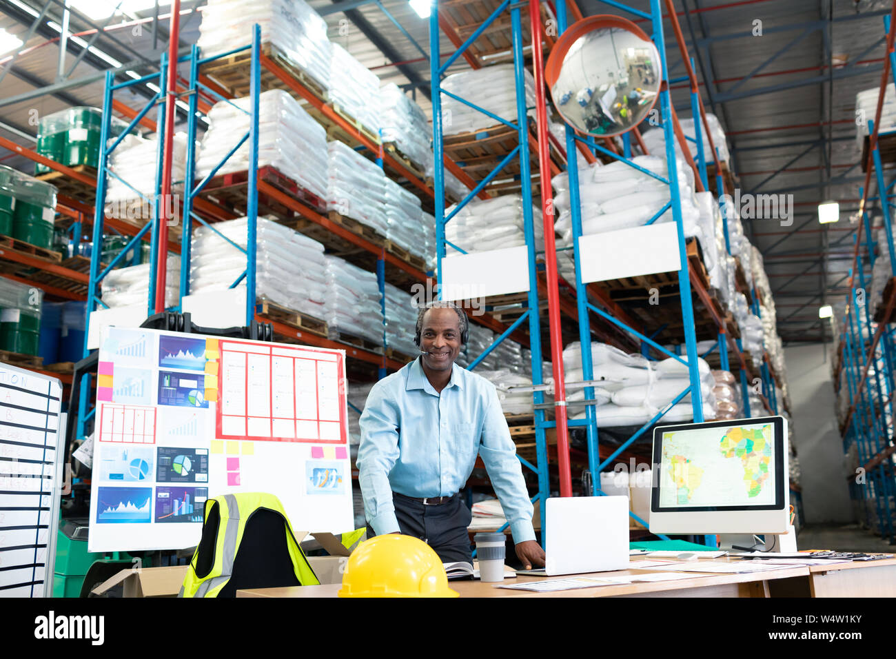 Male supervisor smiling at desk in warehouse Stock Photo - Alamy