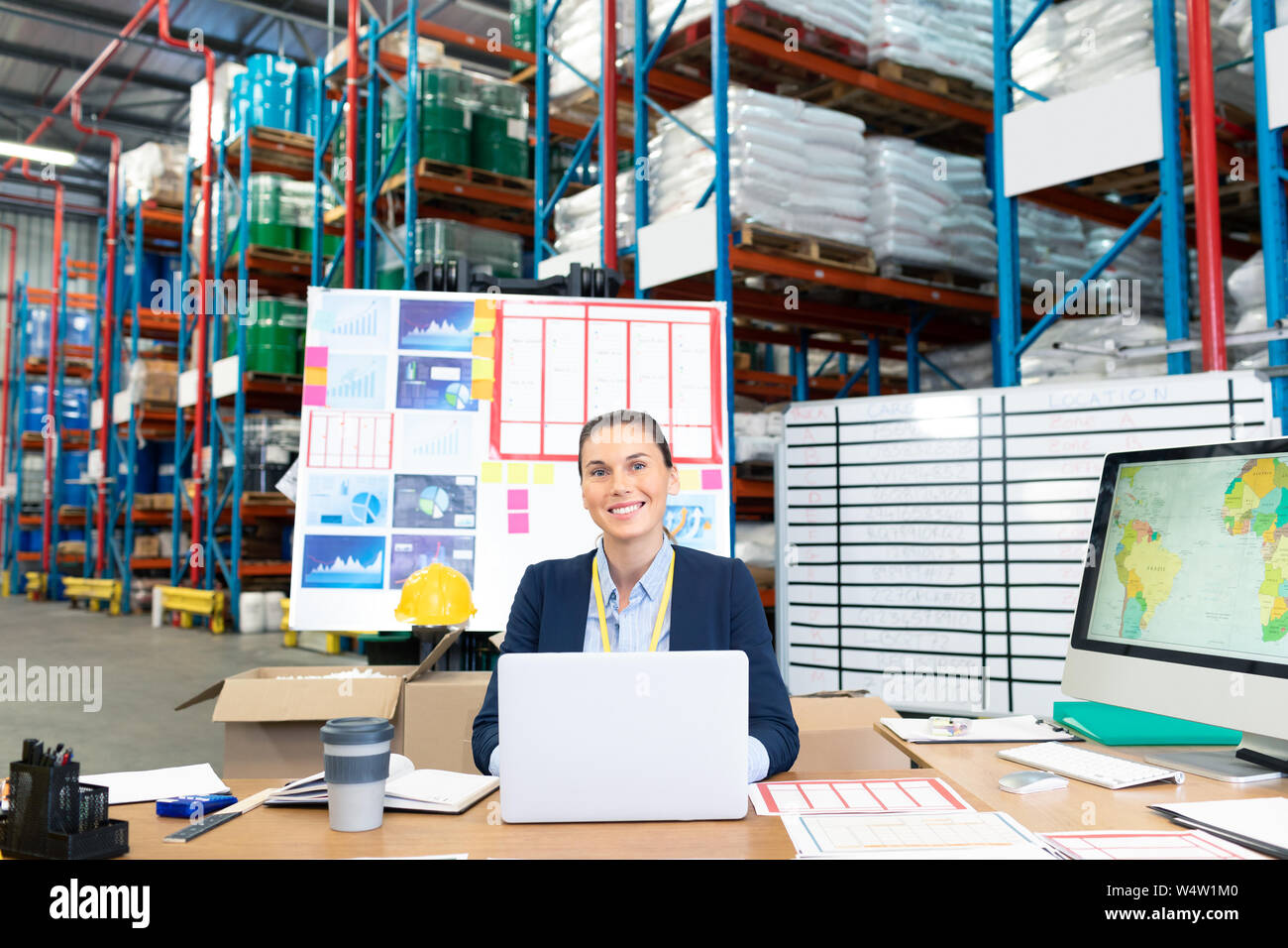 Female manager using laptop at desk in warehouse Stock Photo - Alamy