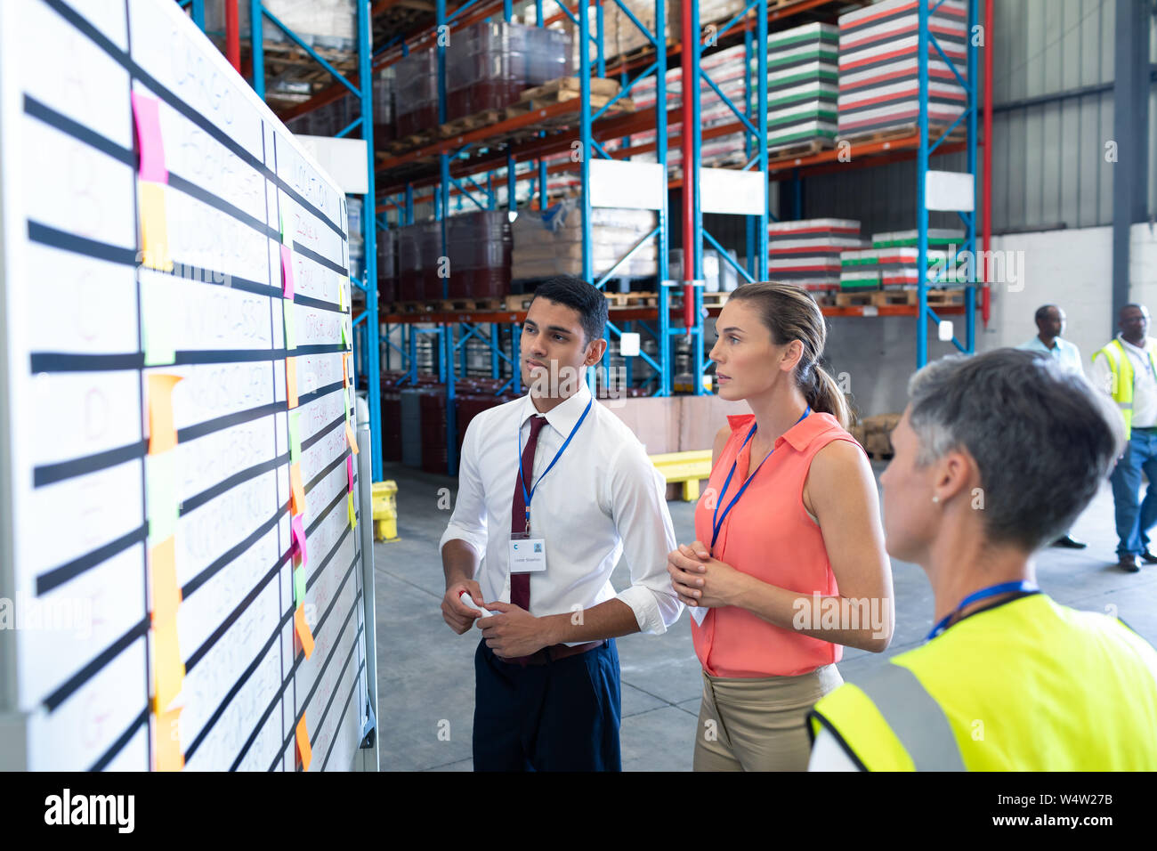 Warehouse staffs looking at whiteboard in warehouse Stock Photo - Alamy