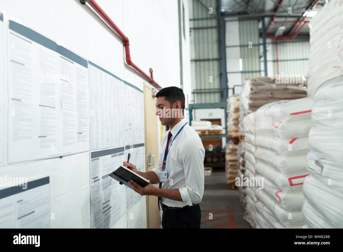 Male supervisor writing on a diary in warehouse Stock Photo - Alamy