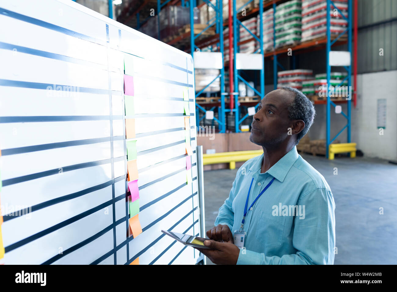 Male supervisor looking at whiteboard in warehouse Stock Photo - Alamy