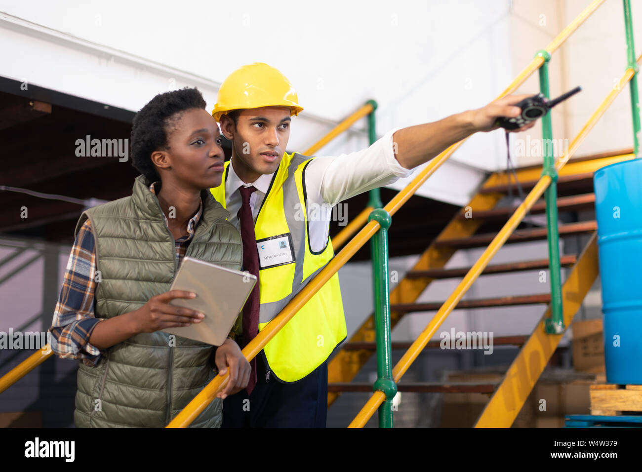 Male supervisor with female worker pointing distance in warehouse Stock ...