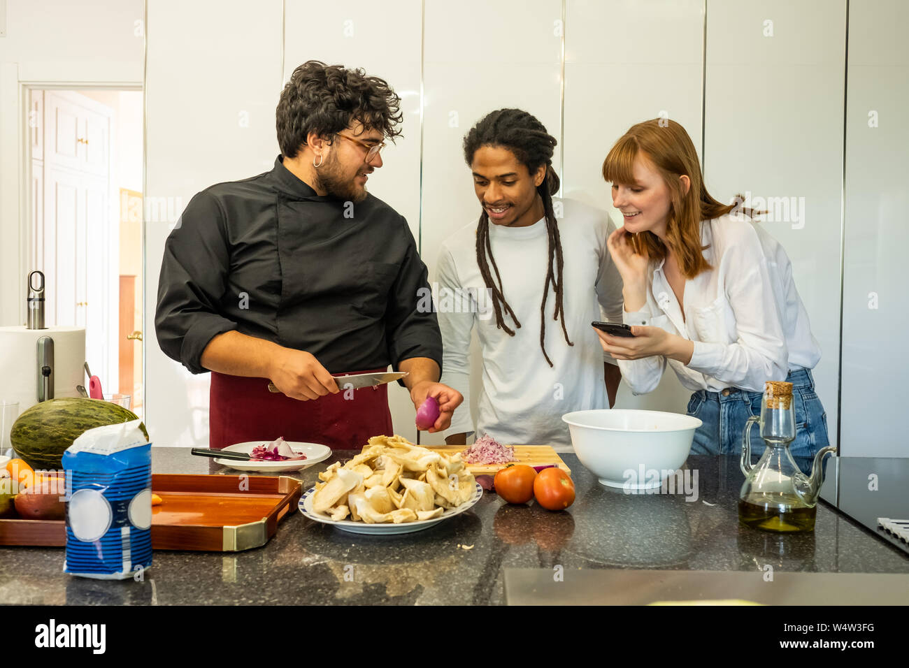 chef teaching a young couple of different breeds how to cook Stock ...