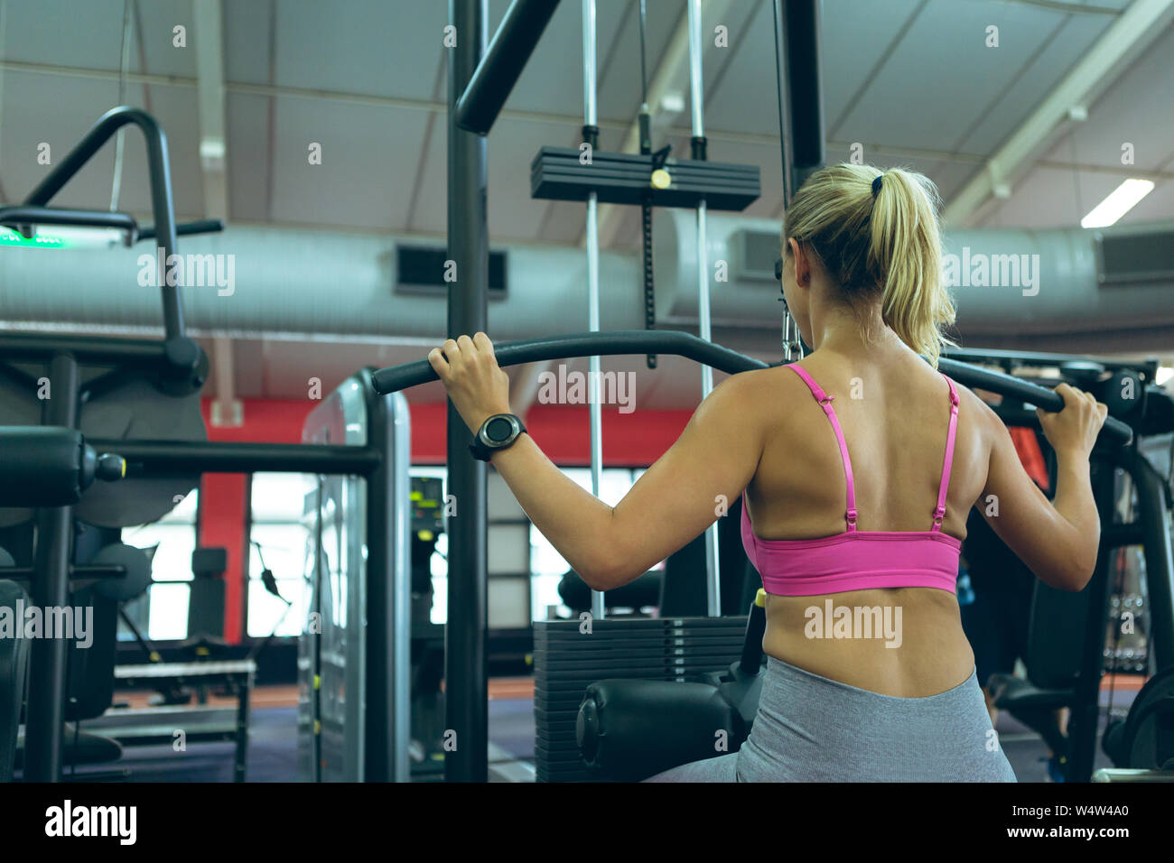 Female athlete exercising with lat pulldown machine in fitness studio ...