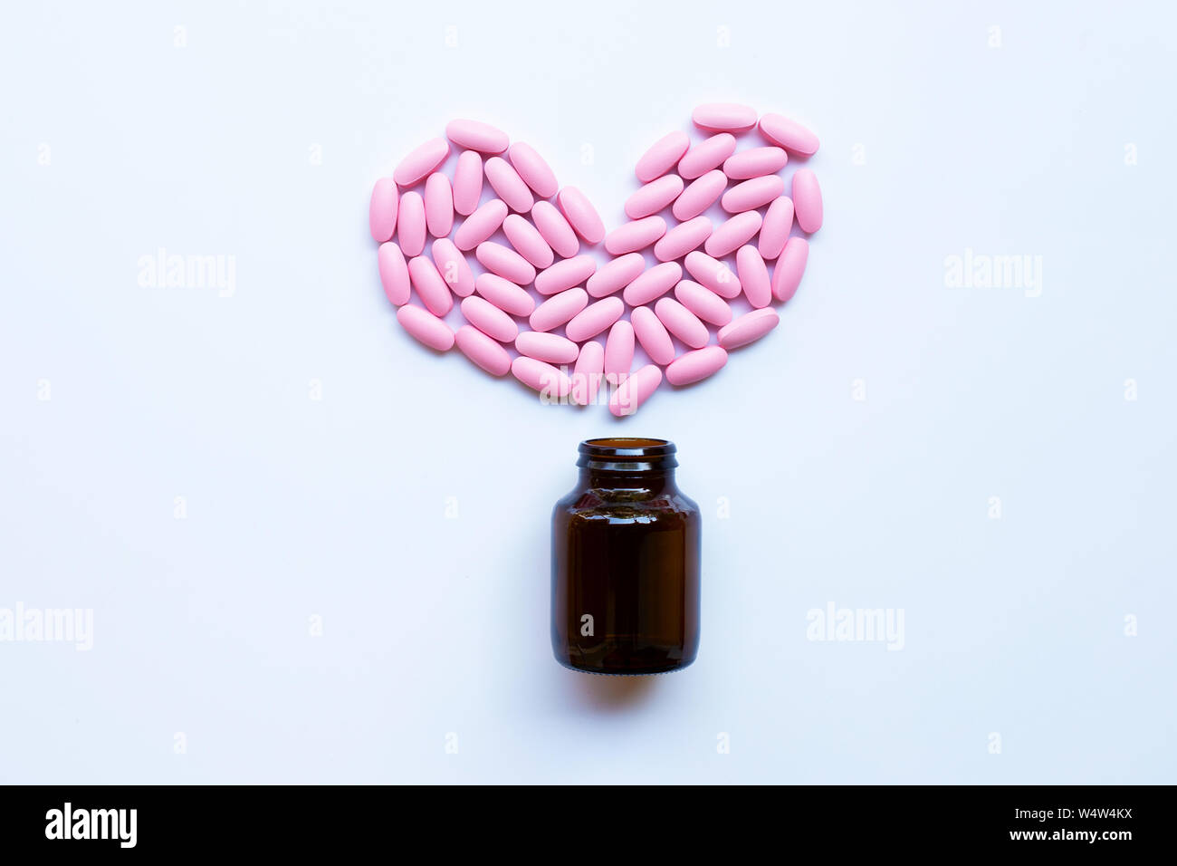 Pink medicine pills on white background. Heart shape Stock Photo - Alamy