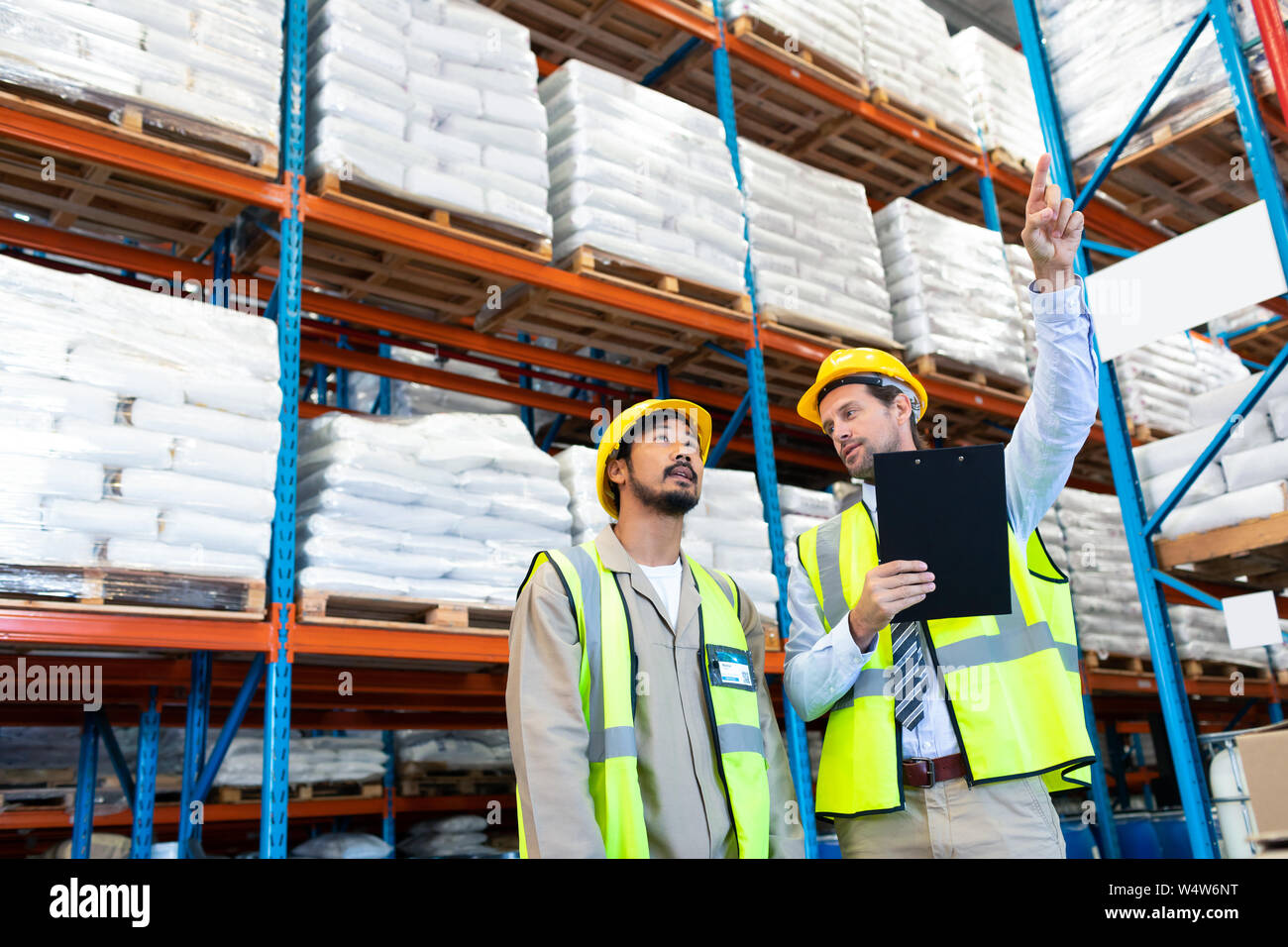 Male supervisor standing with worker and pointing at distance in ...