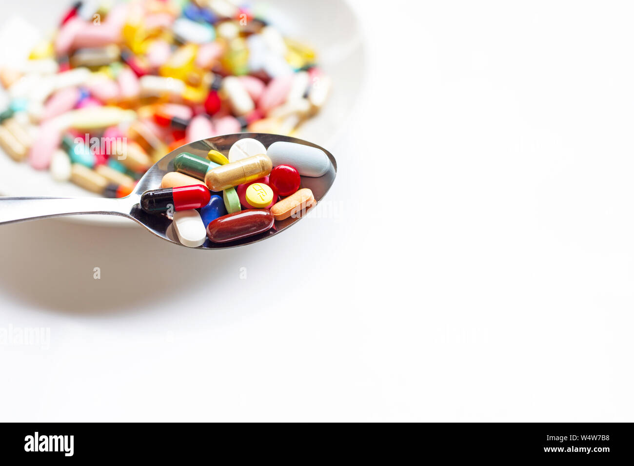 Various types of tablets, capsules and pills on spoon with colorful ...