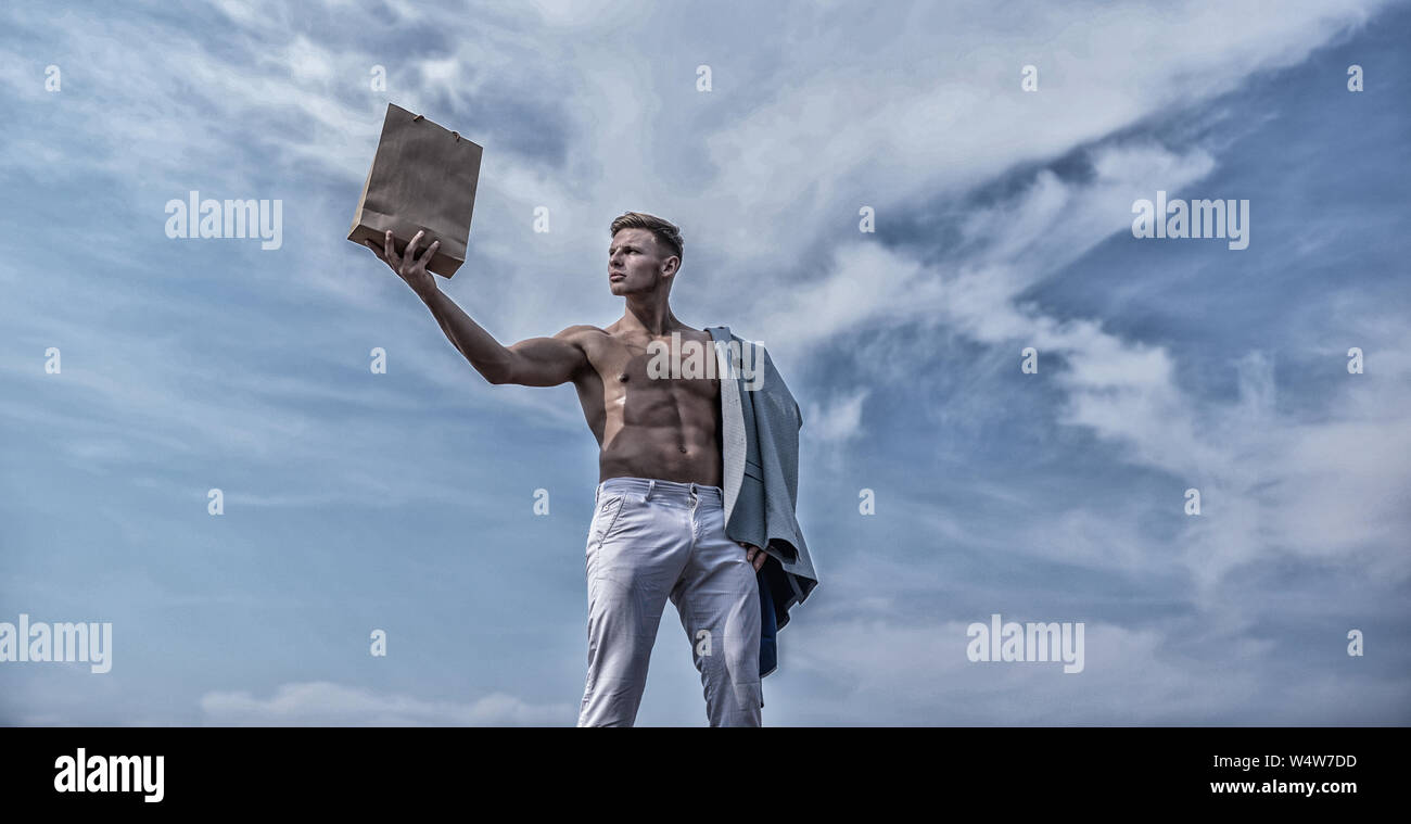 Man muscular athlete hold shopping bag sky background. Hot sales and ...