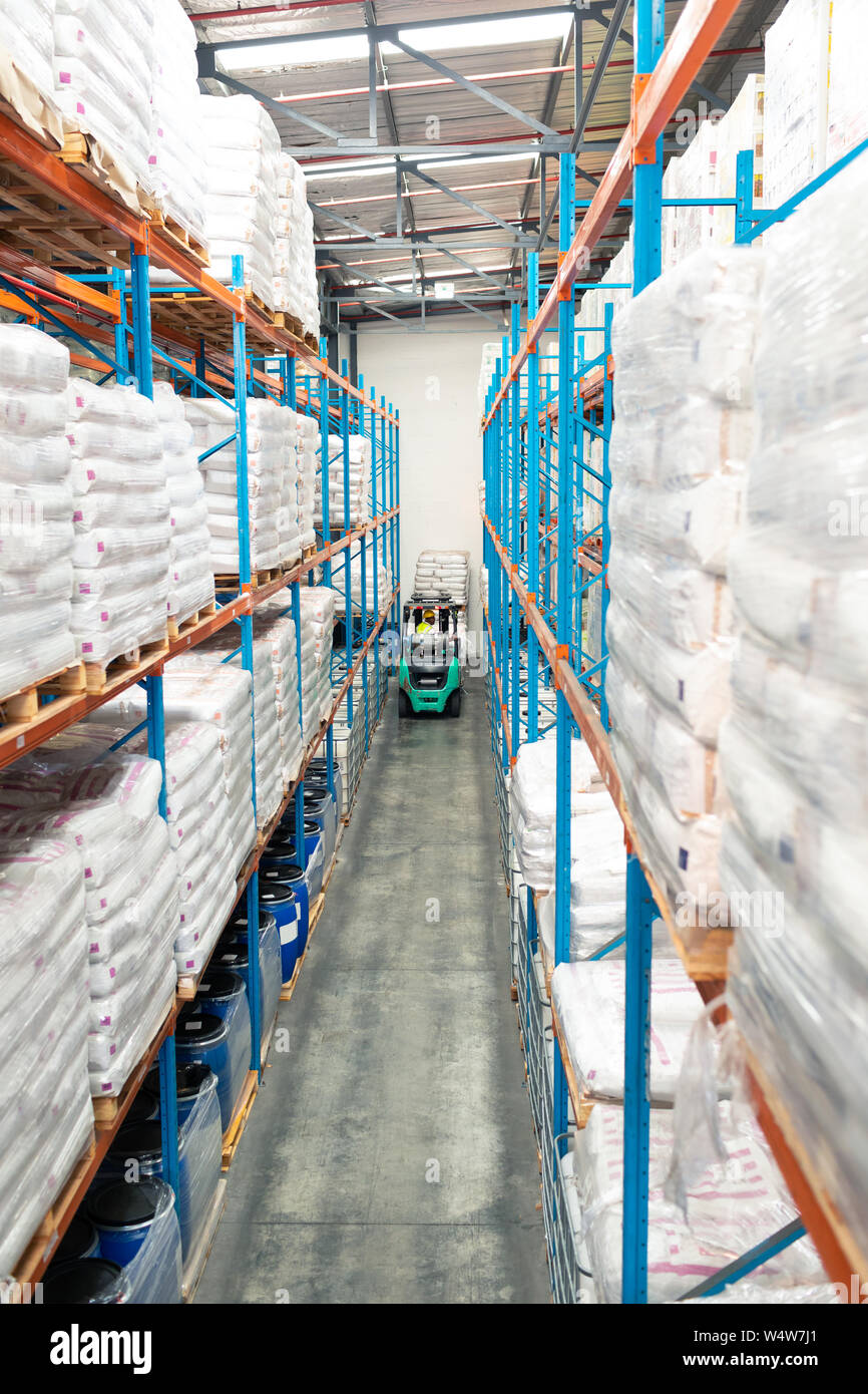 Worker driving forklift in warehouse Stock Photo - Alamy