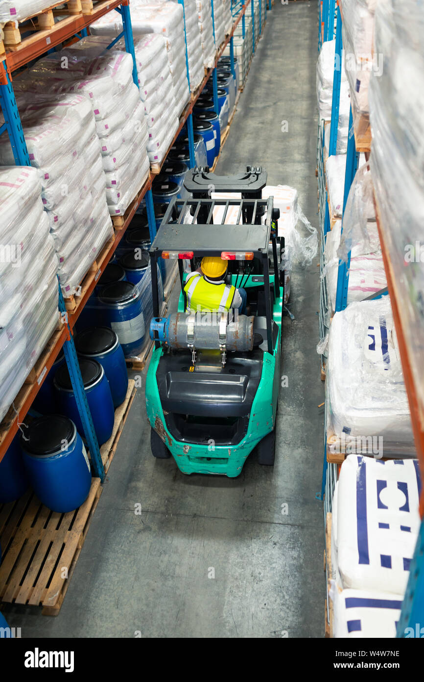 Worker driving forklift in warehouse Stock Photo - Alamy