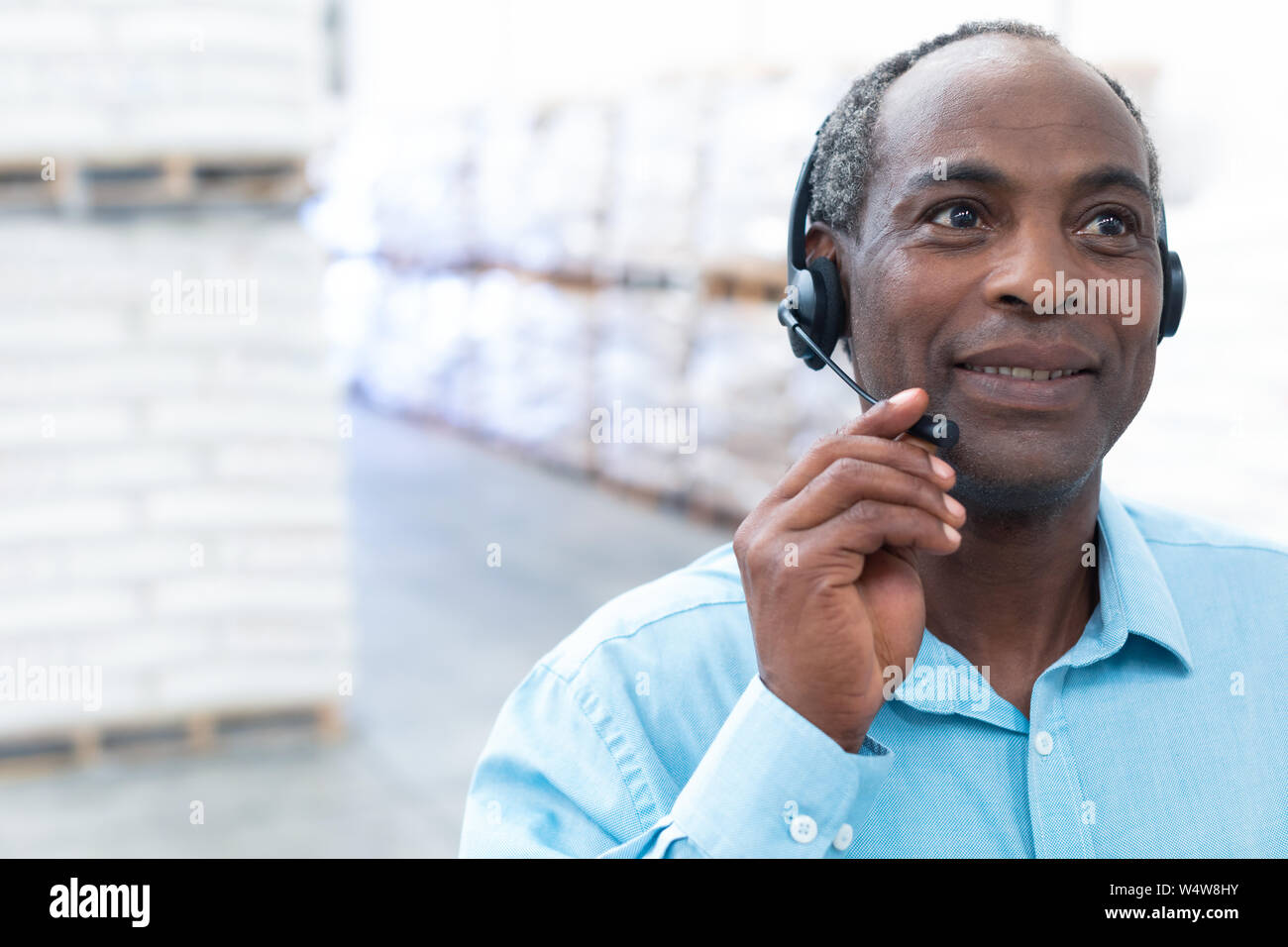 Male supervisor talking on headset in warehouse Stock Photo - Alamy