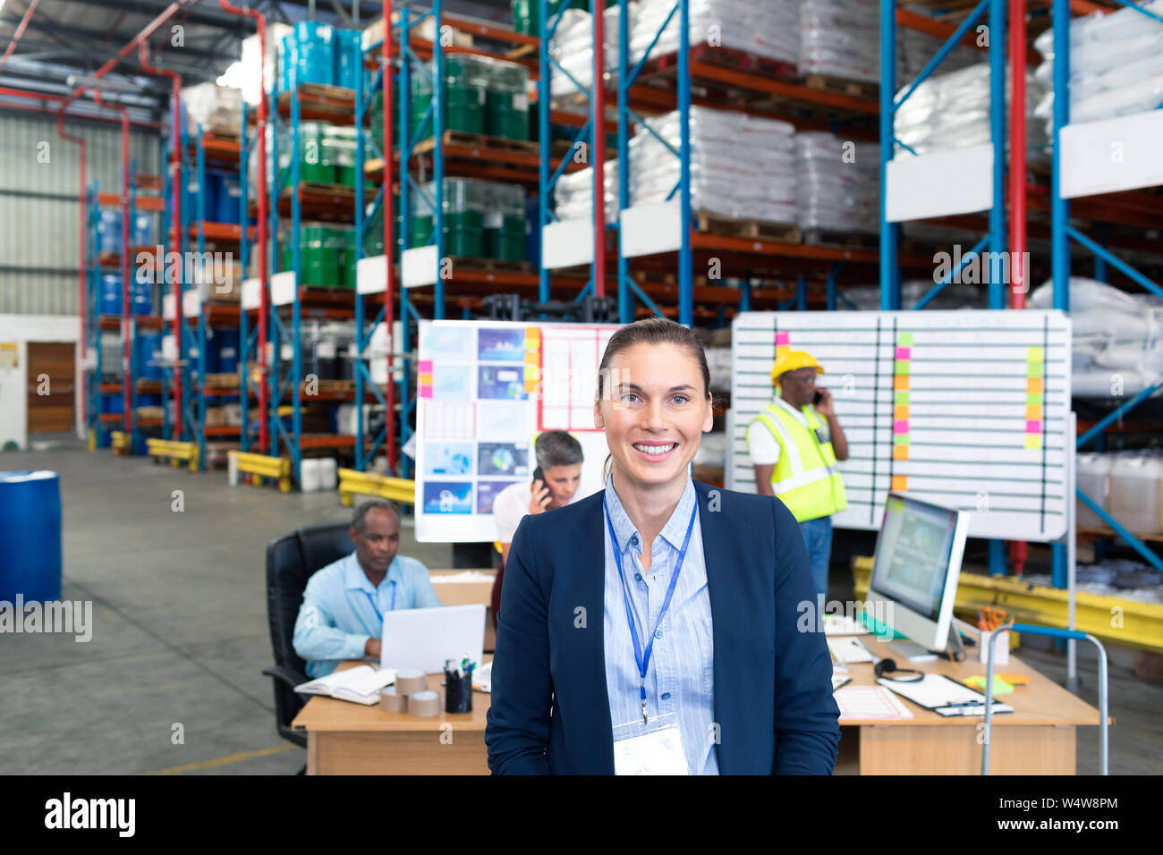 Female manager looking at camera in warehouse Stock Photo - Alamy