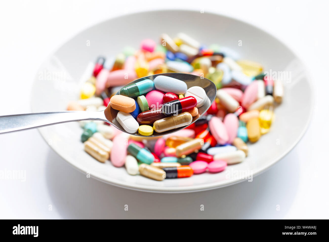 Various types of tablets, capsules and pills on spoon with colorful ...