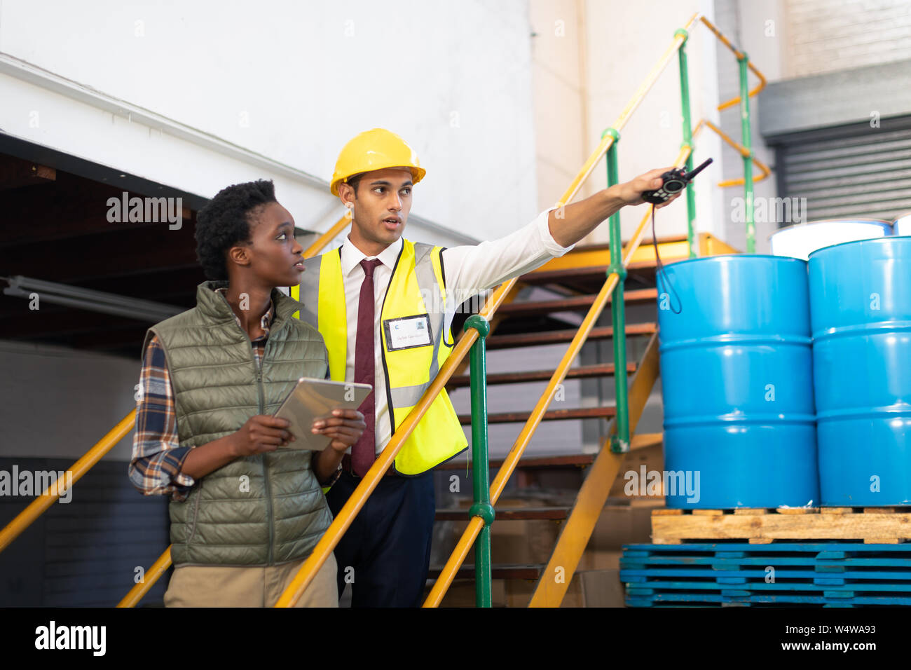 Male supervisor with female worker pointing distance in warehouse Stock ...