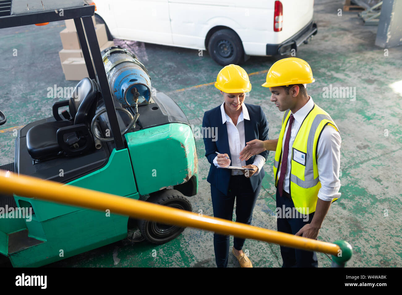 Female manager and male supervisor discussing over clipboard in ...