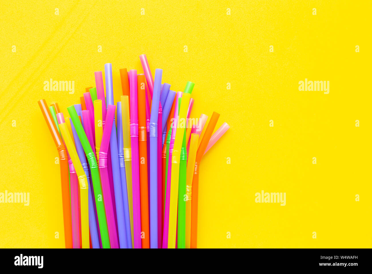 Colorful plastic straws on yellow background. Plastic waste pollution ...