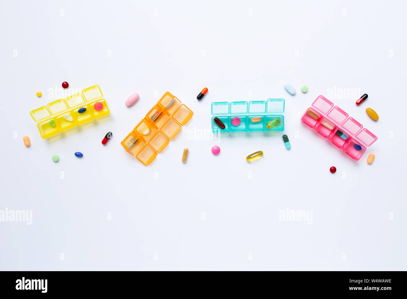 Many colored tablets and capsules with pill box isolated on white ...