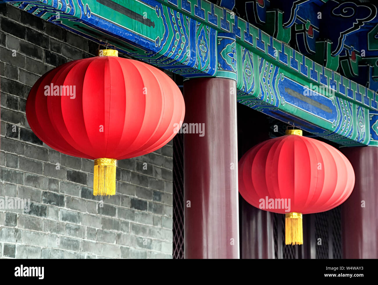 Two large red chinese lanterns hanging from architectural beams on a ...