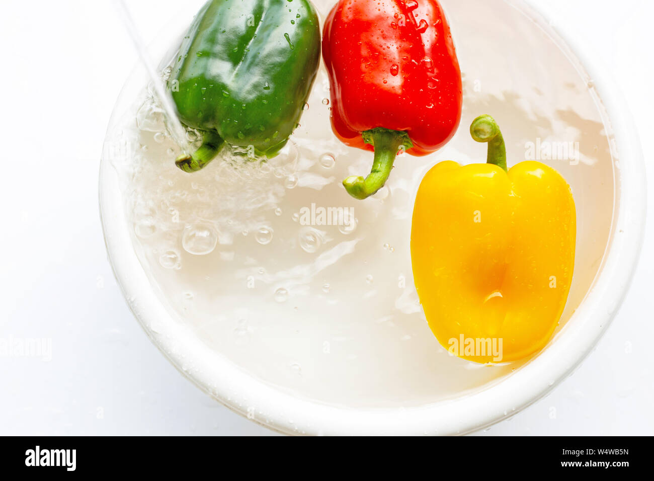 Bell pepper soaked in water. Washing fresh vegetables on white ...
