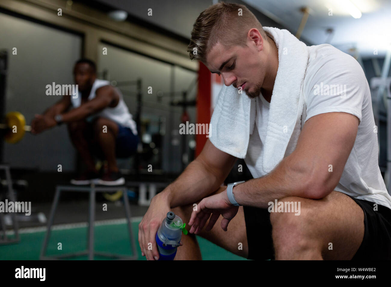 Male athletic checking time on watch in fitness center Stock Photo - Alamy